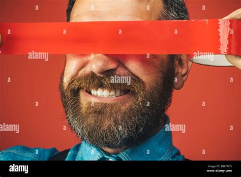 Smiling Bearded Man Wrapping Insulating Tape Over His Eyes Closeup
