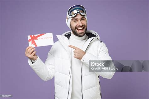 흰색 윈드 브레이커 재킷 스키 고글 마스크 포인트 검지 손가락에 쾌활한 스키 어맨은 보라색 배경에 고립 된 산에서 주말 겨울을 보낸다 사람들 라이프 스타일 취미 개념 선물에