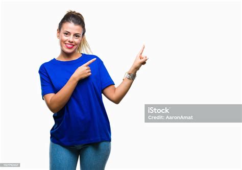 젊은 아름 다운 여자 캐주얼 블루 T 셔츠를 입고 분리 된 배경 웃 고 측면에 두 손과 손가락을 가리키는 카메라를 보고 T 셔츠에 대한 스톡 사진 및 기타 이미지 Istock