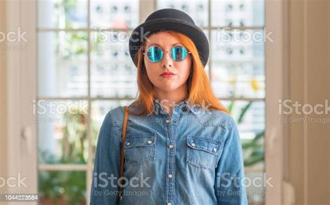 세련 된 빨간 머리 여자 얼굴에 심각한 표정으로 선글라스 중산 모자를 입고 간단 하 고 카메라를 보고 자연 결심에 대한 스톡 사진 및 기타 이미지 Istock