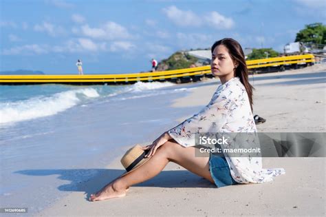 화창한 낮 시간에 바다 옆의 열대 해변에서 무릎에 밀짚 모자를 쓰고 해변에 앉아있는 걱정스러운 여성 외로운 소녀는 해변가에 혼자 앉아 긴장을 풀고 생각합니다 인간의 감정