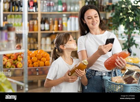 Girl With Mother Customers At Shop Scans Qr Code On Juice Package Using