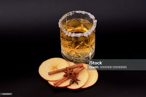 테두리 주위에 설탕이 든 사이다 한 잔과 검은 색 배경에 계피와 아니스가 들어간 잘 익은 사과 조각 0명에 대한 스톡 사진 및