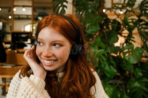 Young Girl Listening Music With Headphones While Sitting In Cafe Stock
