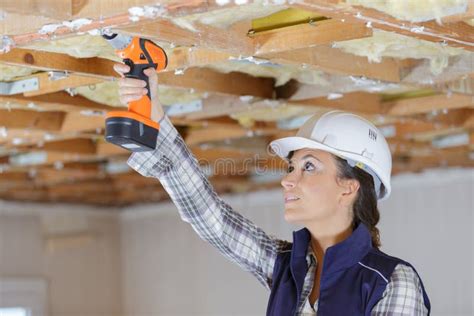 Female Builder Using Cordless Drill Wooden Ceiling Joist Stock Photos