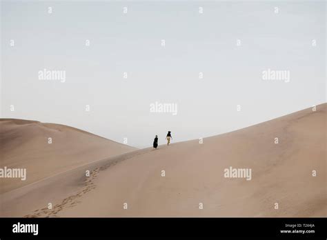 Namibia Namib Back View Of Two Women Walking On Desert Dune Stock