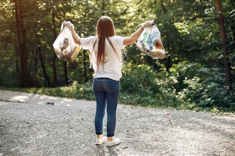 Menina Recolhe Lixo Em Sacos De Lixo No Parque Foto Grátis