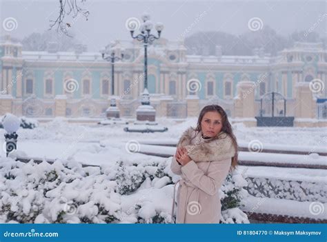Портрет зимы женщины в белом пальто во время снежностей в парке
