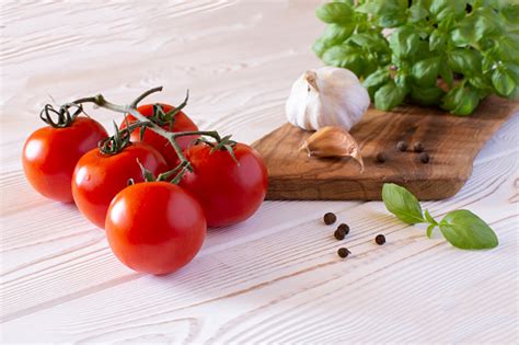 바질 마늘 향신료를 곁들인 신선한 토마토가 소박한 스타일로 나무 흰색 테이블에 올려놓습니다 복사 공간 건강한 생활방식에 대한
