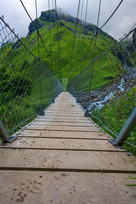 Premium Photo A Suspension Bridge Between Mountains Overgrown With Grass