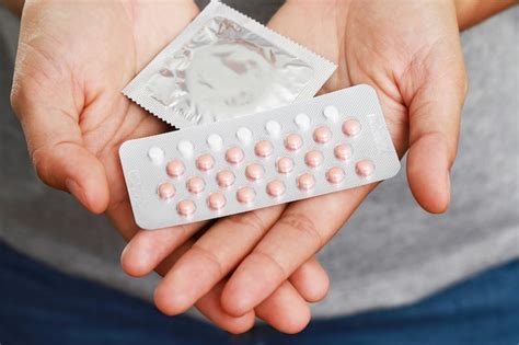 Mujer Sosteniendo Píldoras Anticonceptivas Y Condones En La Mano