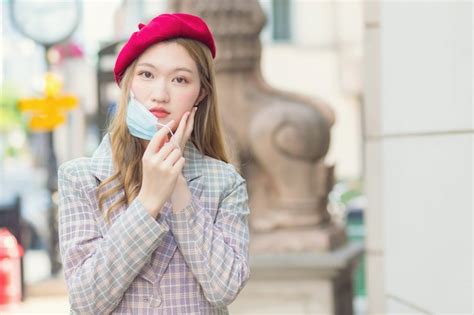 아시아 여성은 양복과 빨간 모자를 쓰고 의료용 얼굴 마스크를 착용하는 동안 피부 문제를 걱정합니다 프리미엄 사진