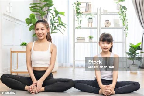 아시아의 젊은 어머니와 딸 세팅은 요가와 명상을 준비하며 집 거실의 요가 매트에서 함께 포즈를 취합니다 피트니스 라이프 스타일