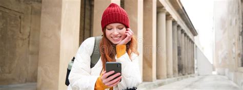 Redhead Girl Tourist With Backpack Uses Mobile Phone To Rent E