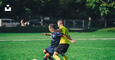 파란색과 노란색 축구 유니폼을 입은 소년은 낮 동안 푸른 잔디밭에서 축구공을 차고 있다 사진 Unsplash의 무료 축구 이미지