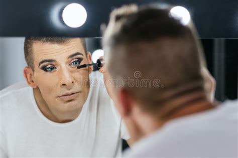 Drag Queen Performer Looking In The Mirror While Applying Mascara On