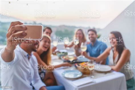 휴대 전화로 저녁 식사 파티에서 셀카를 찍는 친구들의 Defocussed 그룹 20 24세에 대한 스톡 사진 및 기타 이미지