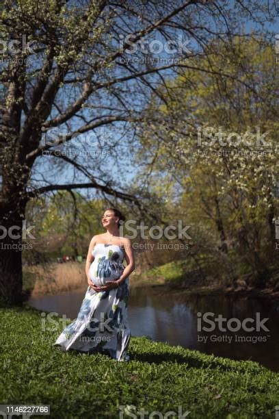 젊은 여행자 임신 한 여자 걷기 달리기 주위를 선회 하 고 꽃 패턴으로 여름 빛 긴 드레스를 입고 꽃 피는 사쿠라 벚꽃 나무 공원에서 그녀의 여가 자유 시간을 즐긴다 개념에