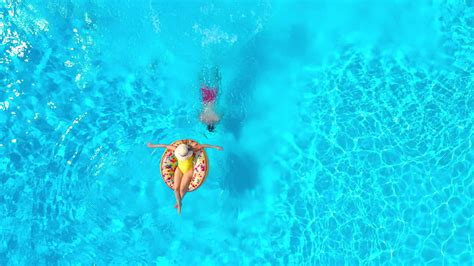 Top View Of A Couple Having Fun In The Pool The Man Swims And The Woman Lies On An Inflatable