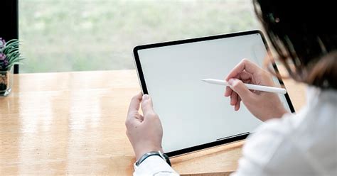 공동 작업 공간에 앉아있는 동안 태블릿 화면에 작성 스타일러스 펜을 사용하여 여성의 손의 클로즈업 이미지 공간을 복사합니다