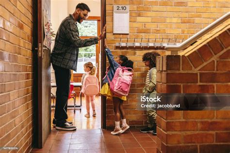 초등학교 교사가 문 앞에서 학생들을 맞이하고 있다 하이파이브로 수업을 환영하는 남자 교사 교사 교육 관련 직업에 대한 스톡 사진 및 기타 이미지 교사 교육 관련 직업