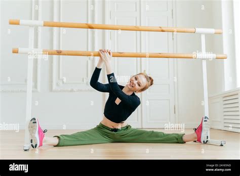 Caucasian Female Ballerina Spreads Legs Sideways Shows Splits Holds