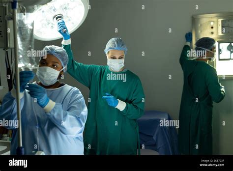 Two Diverse Female Surgical Techs Adjusting Light And Iv Bag In