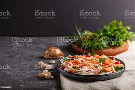 검은 색 콘크리트 배경과 린넨 직물에 회색 세라믹 접시에 새우 또는 새우와 작은 문어와 쌀 국수 측면 보기 복사 공간 선택적