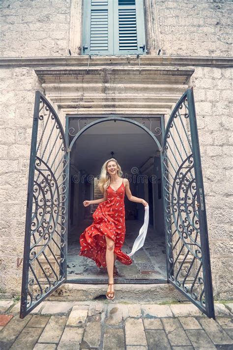 Joyful Blonde Jumping In Red Sultry Dress Feeling Happy Old Building