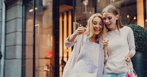 웃는 딸에게 가게에서 산 옷을 보여주는 쾌활한 중년 여성의 초상화 그들은 부티크 근처 거리에 서 있습니다 사진 Unsplash의 사람 이미지