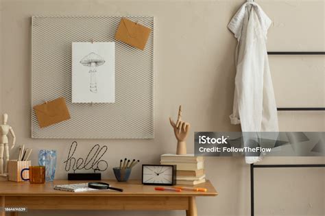 모형 포스터 프레임 나무 책상 등나무 찬장 책 검은 사다리 유리 갈색 벽 조각품 및 개인 액세서리가 있는 아늑한 사무실