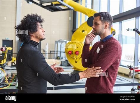 Two Engineers In Deep Discussion About Robotics Technology Standing In
