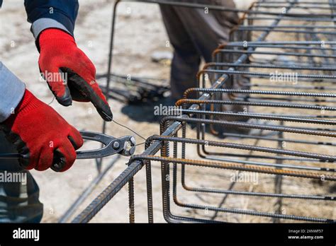 A Worker Uses Steel Tying Wire To Fasten Steel Rods To Reinforcement