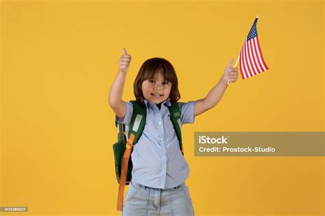 국제 유치원 수업 배낭을 메고 미국 국기를 들고 엄지손가락을 치켜드는 제스처 여유 공간을 보여주는 귀여운 소년 4 5세에 대한 스톡 사진 및 기타 이미지 Istock