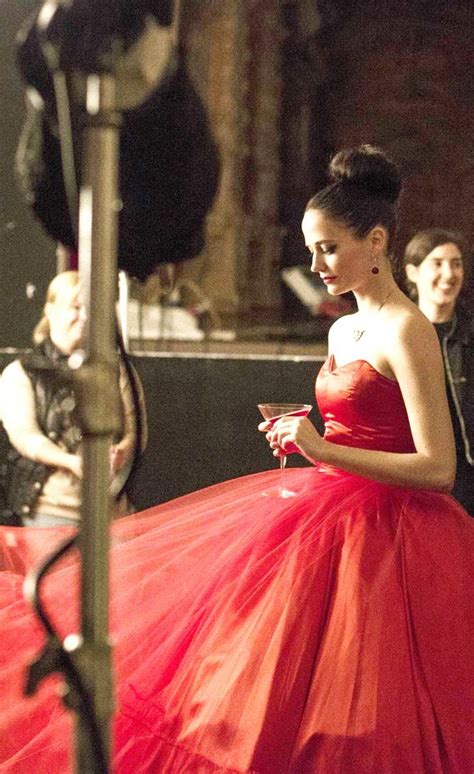 A Woman In A Red Dress Is Looking At Her Cell Phone While Another Man