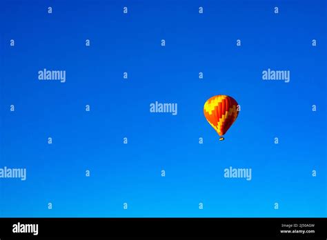 Hot Air Balloon Single Red And Yellow Colored Hot Air Balloon Isolated On Clear Blue Sky