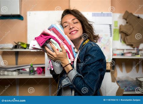 Woman Fashion Designer Hugging Gently A Pile Of Clothes In Hands Stock