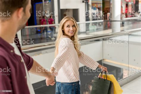 동안 그녀는 쇼핑몰에서 그를 최고의 쇼핑 가방 웃는 여자 친구의 손을 잡고 남자의 부분 보기 고객에 대한 스톡 사진 및 기타