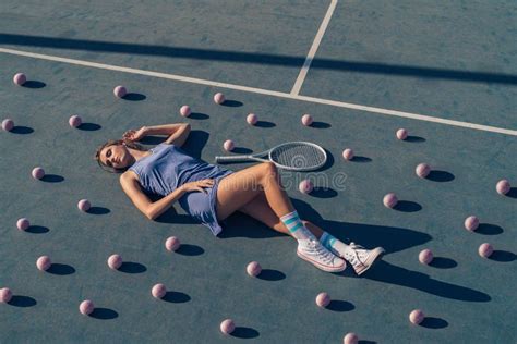 Closeup Of A Tennis Player Lying On The Sunlit Blue Tennis Court With