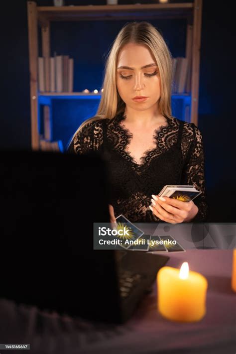 여성 점쟁이는 예측을 위해 타로 카드를 읽고 웹캠 랩톱 컴퓨터 새로운 서비스 및 중소기업을 통해 서비스를 제공하여 고객에게 운세를 알려줍니다 화상 회의에 대한 스톡 사진 및