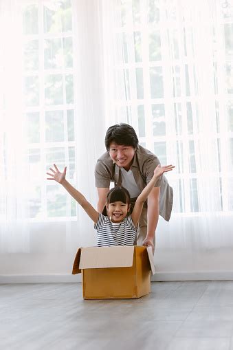 행복한 아시아 가정은 집에서 즐거운 시간을 보냅니다 정크 모델 자동차의 거실 주위에 골판지 상자를 밀고있는 아버지와 사랑스러운