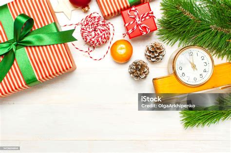 새해 또는 크리스마스 배경 복고풍 알람 시계 소나무 가지 원뿔 선물은 복사 공간이있는 흰색 나무 배경 상단보기에 장난감 빨간 공을 선물합니다 크리스마스 타이머 크리스마스