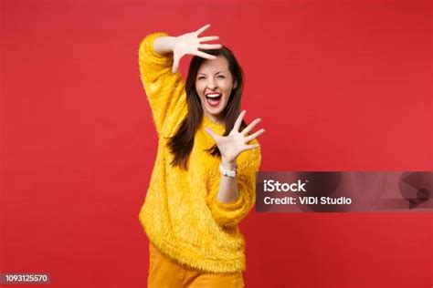 노란 털 스웨터 표시에 재미 있는 웃음 젊은 여자의 초상화 스튜디오에서 밝은 빨간색 배경에 고립 확산 손가락 손바닥 사람들이 진심으 감정 라이프 스타일 개념 복사 공간을