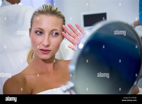 Woman Checking Her Skin In The Mirror After Receiving Cosmetic
