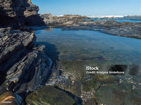 포르투갈 빌라 노바 데 밀폰테스 근처의 파도와 날카로운 바위 돌 절벽이 있는 야생 로타 비센티나 코아스의 작은 달콤한 물 석호 화창한 날 푸른 하늘 0명에 대한 스톡 사진