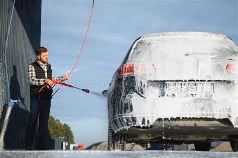 A Man Washes Off The Foam While Washing The Car A Vehicle Is Engulfed
