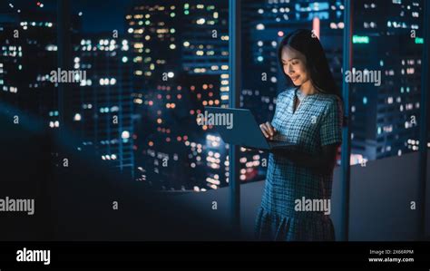 Financial Analyst Using Laptop Computer Standing Next To Window With