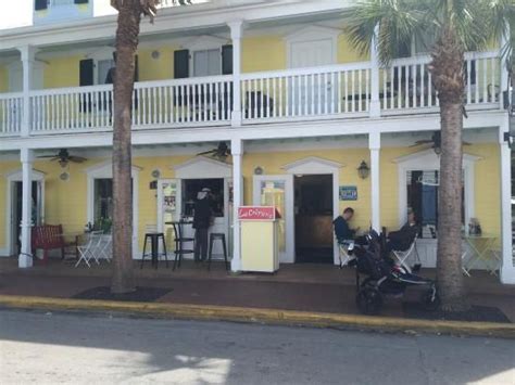 A Yellow Building With White Balconies And Palm Trees On The Street In