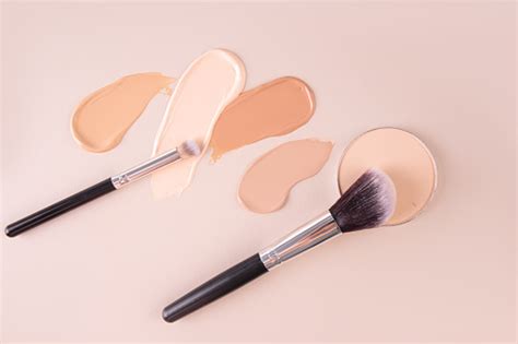 다양한 톤의 아름다운 파운데이션 스트로크 두 개의 메이크업 브러시 베이지 색 배경에 컴팩트 한 파우더의 둥근 블록 평면도