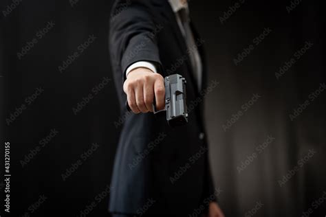 拳銃を構えるスーツ姿の人物 ภาพถ่ายสต็อก Adobe Stock